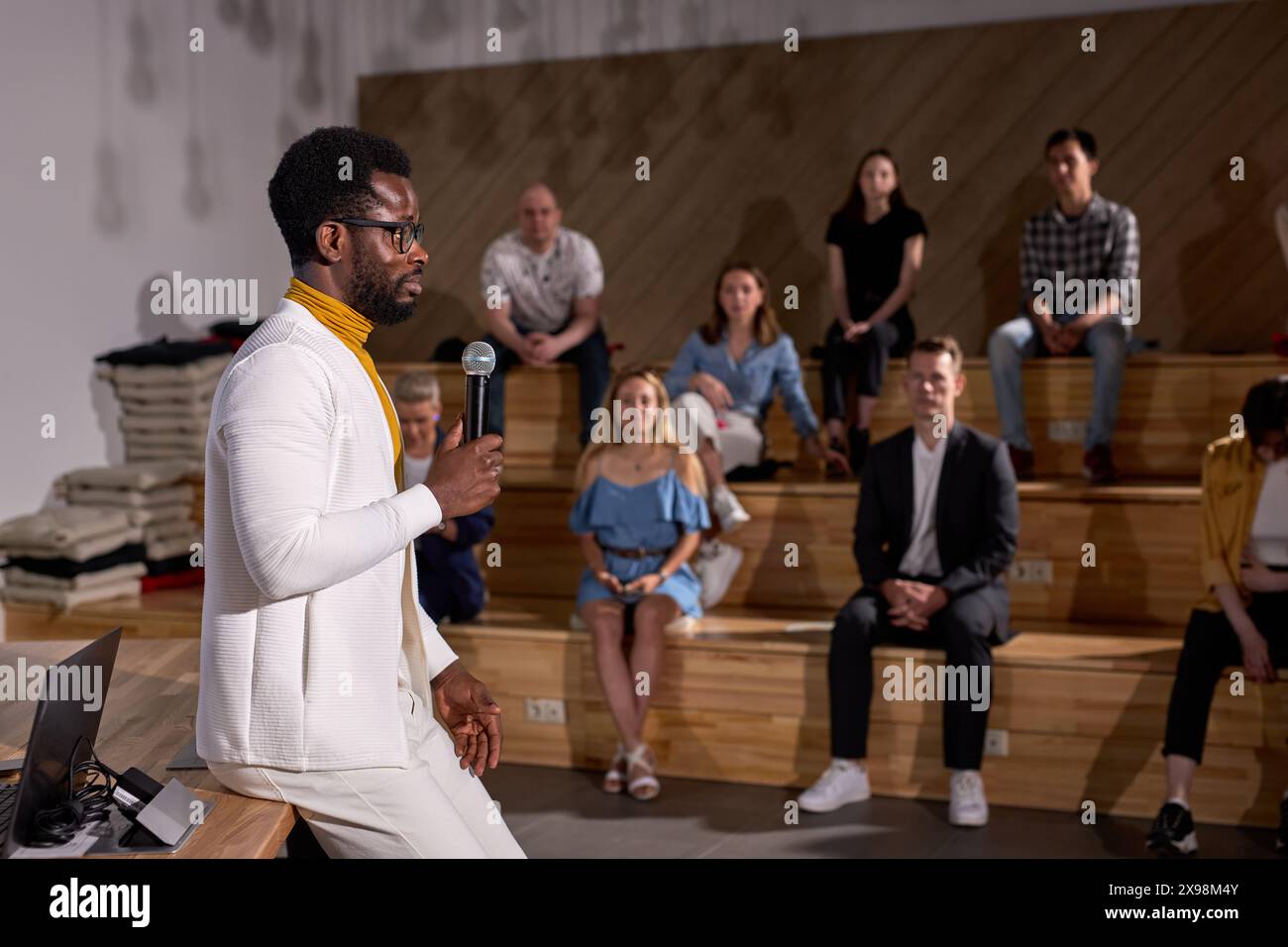 Afro lecturer presenting lesson with microphone to caucasian group of ...