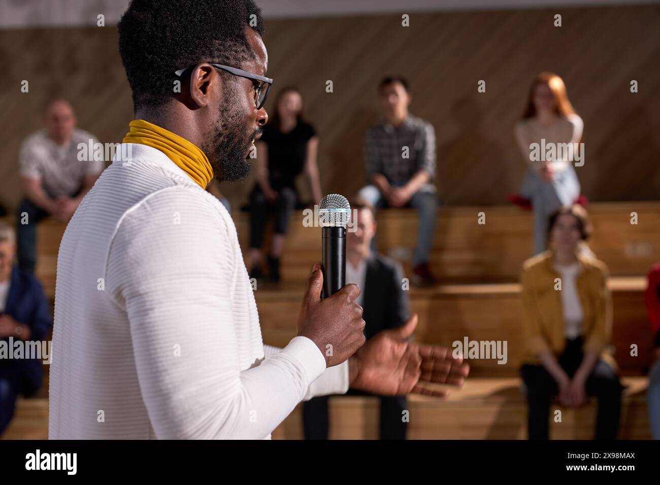 African lecturer presenting lesson with microphone to caucasian group ...