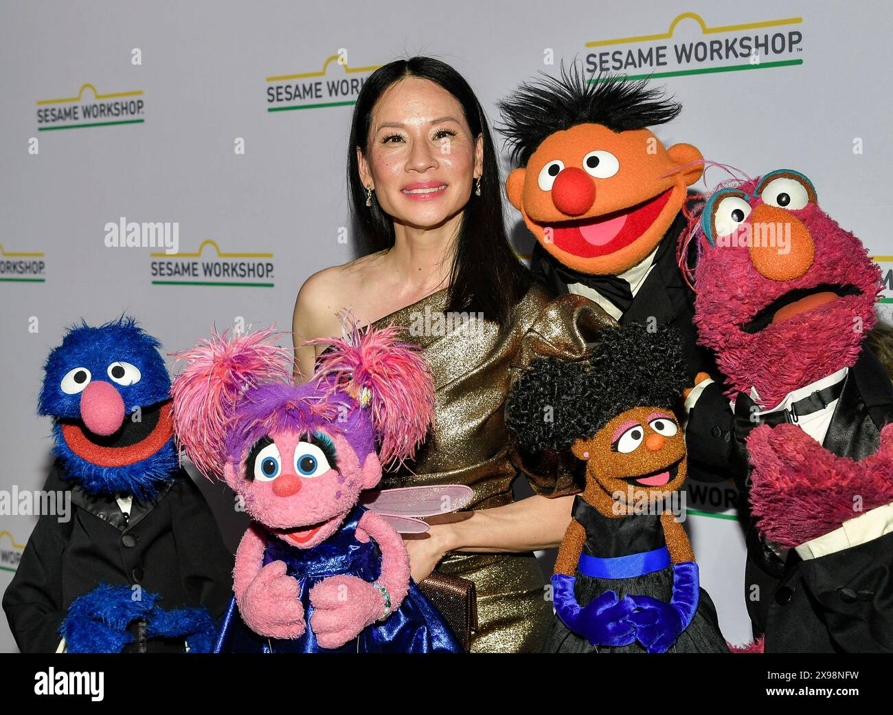 Lucy Liu, center, poses with Muppet characters at the Sesame Workshop ...