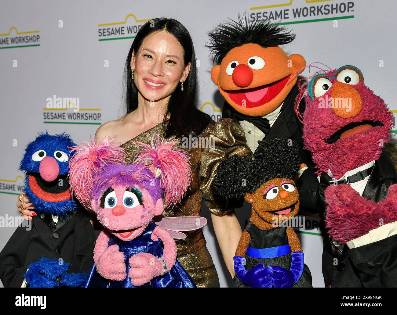 Lucy Liu, center, poses with Muppet characters at the Sesame Workshop ...