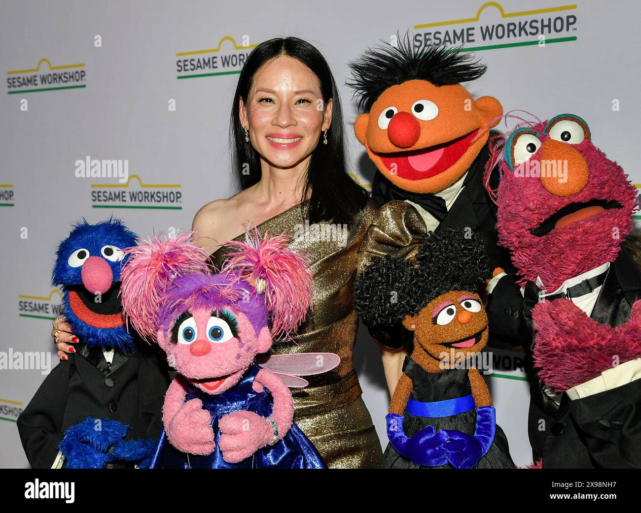 Lucy Liu, center, poses with Muppet characters at the Sesame Workshop ...