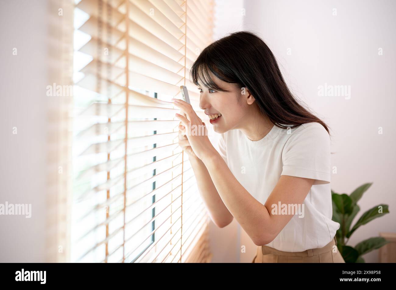A Curious Nosy Young Asian Woman Spying On Neighbor From Window Looking Through The Window
