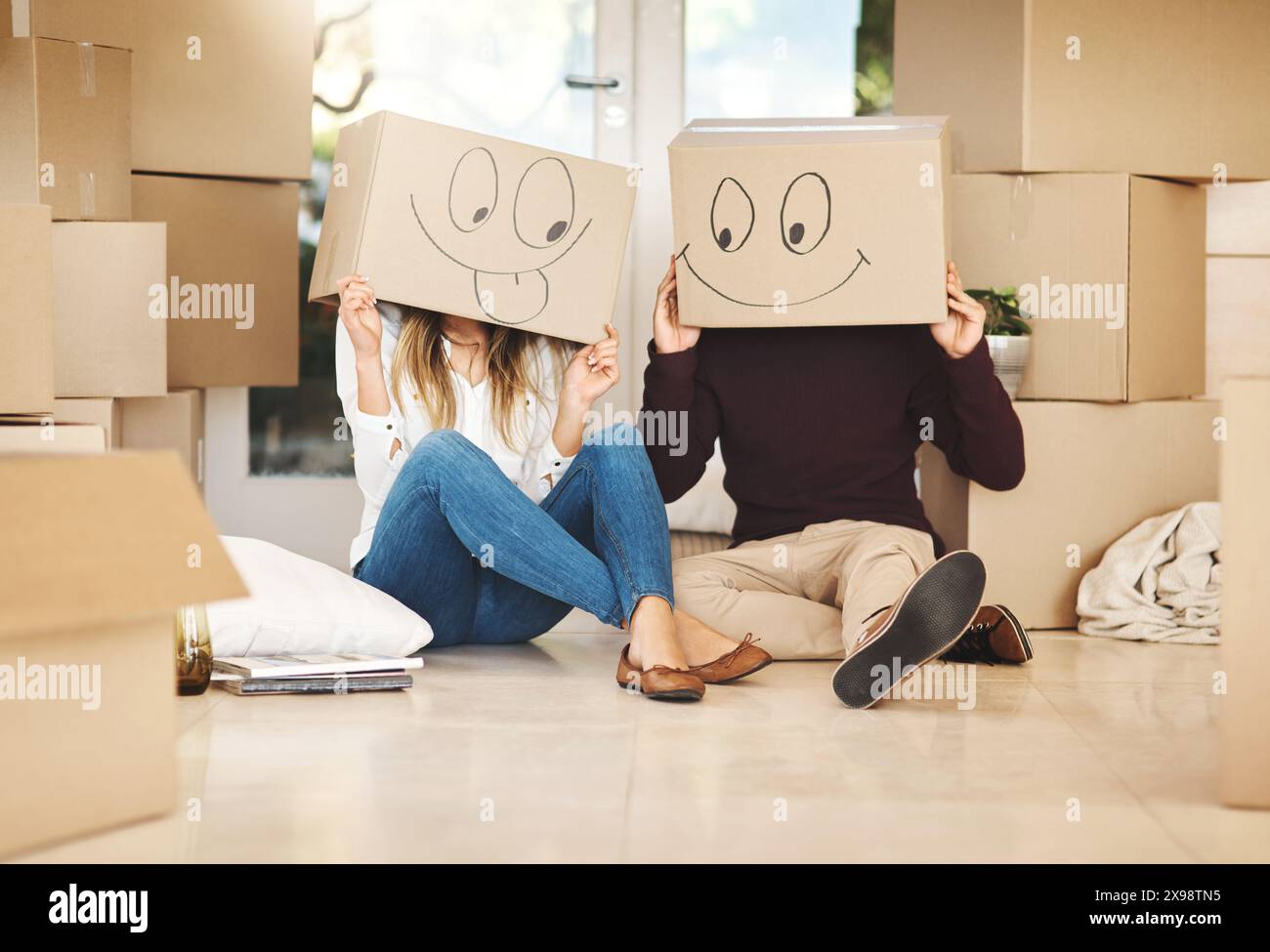 Moving, couple and cardboard box with smiley face in new home for real ...