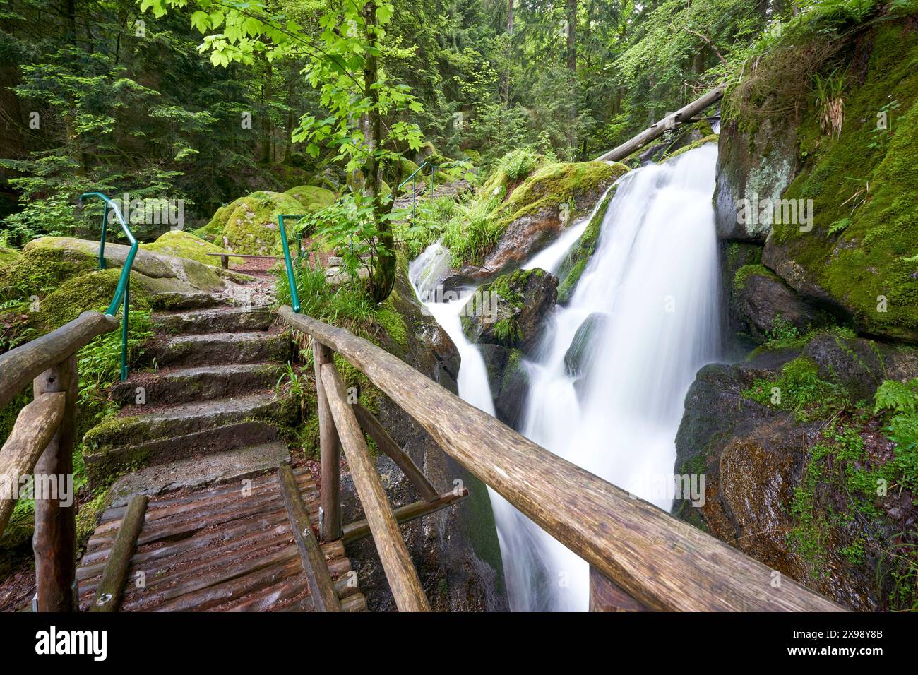 Vibrant scene, waterfall cascading down mossy rocks, wooden staircase ...