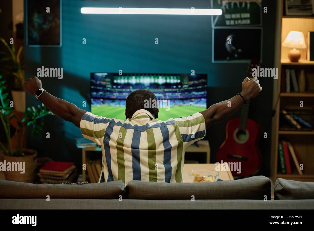 Back view of unrecognizable young Black man sitting on sofa in living ...