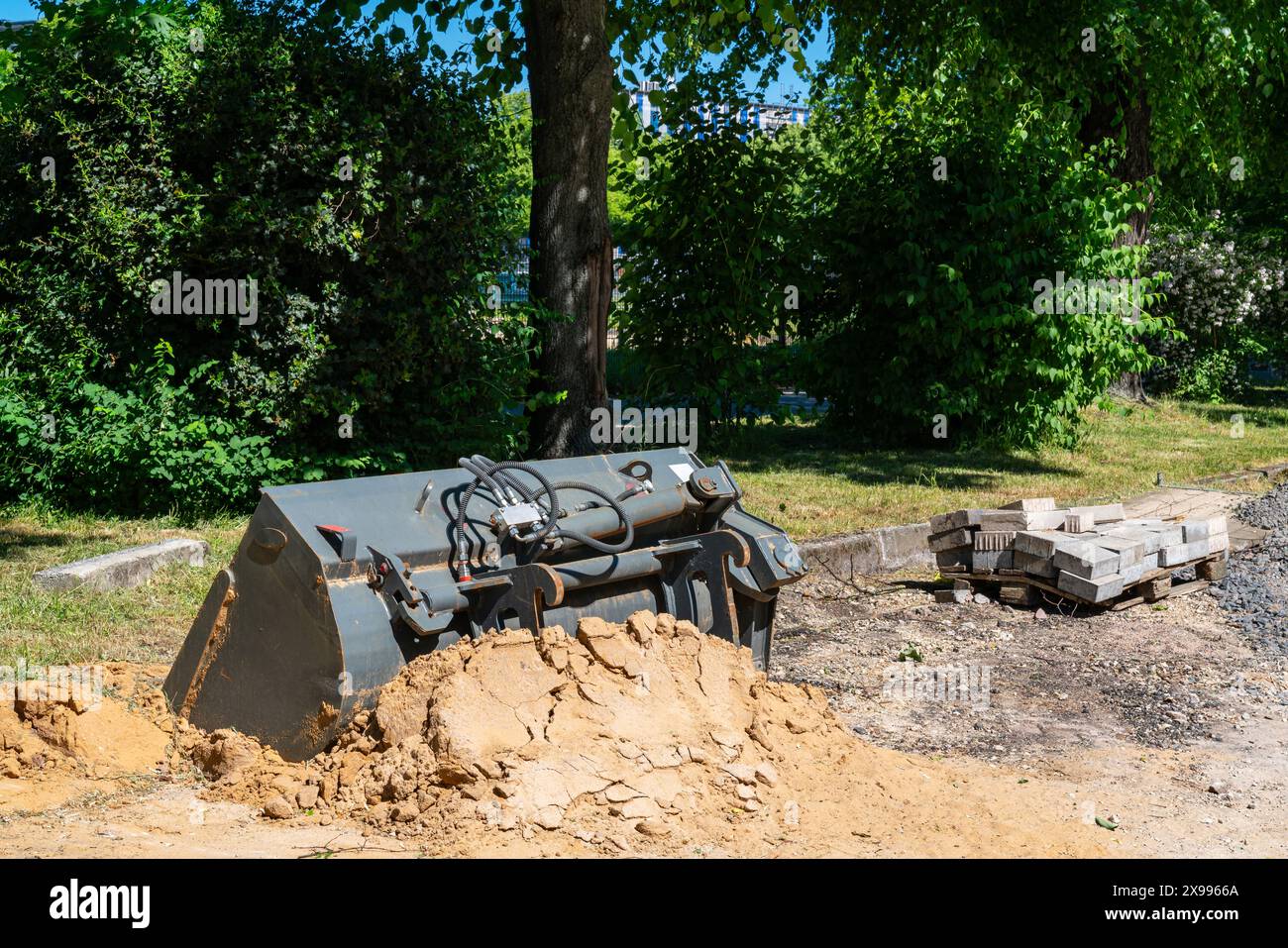 Excavator bucket on a pile of earth and remains of road tiles on a ...