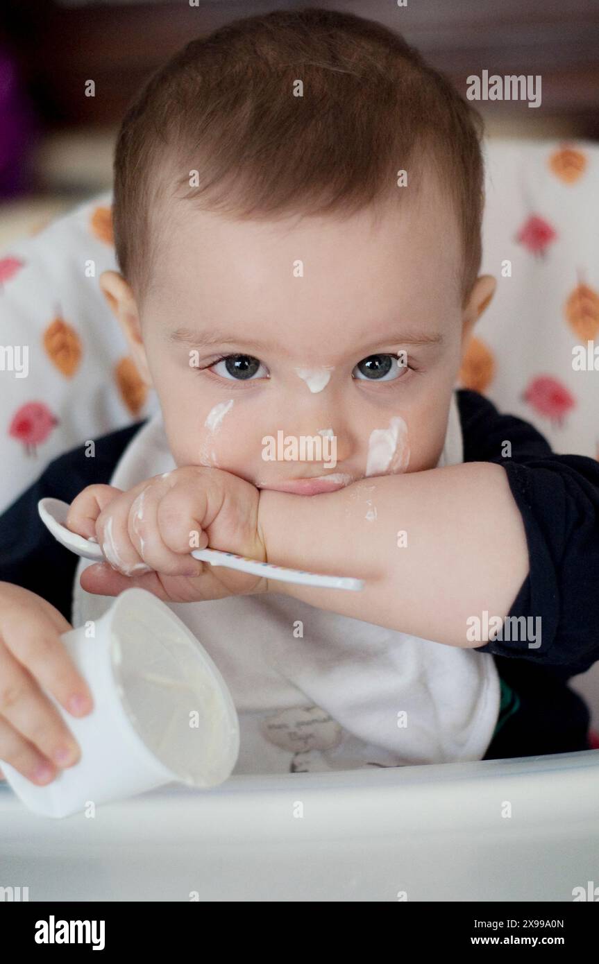 Toddler Sitting in Highchair and Eating Yogurt. Baby Learning to Eat ...