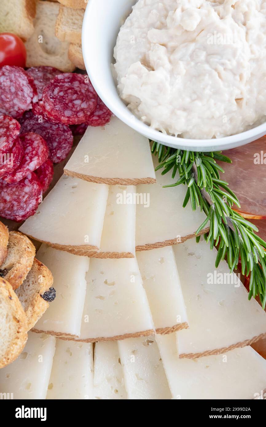 Assortment of sliced cheeses and cured meats set on a charcuterie board ...