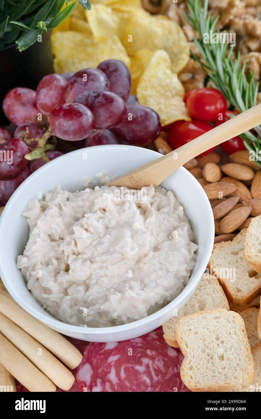 Close-up of a creamy dip in a white ceramic bowl, surrounded by a ...