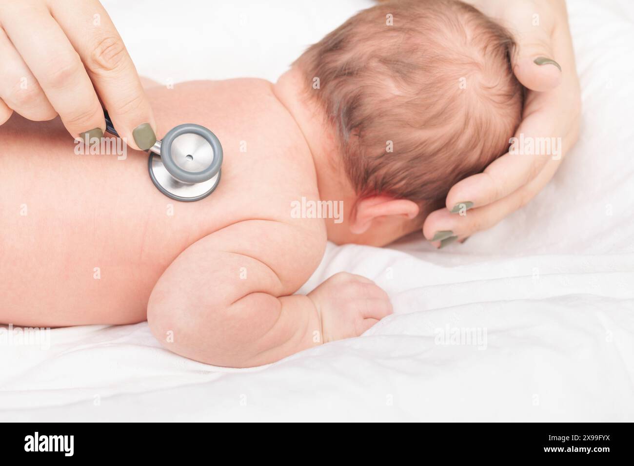 Newborn medical exam - doctor checking heart beat and lungs with ...