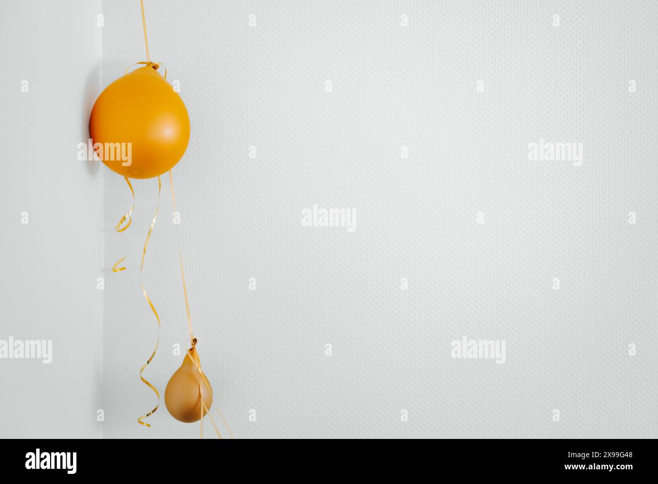 Deflated yellow balloons on golden string white background. After party ...