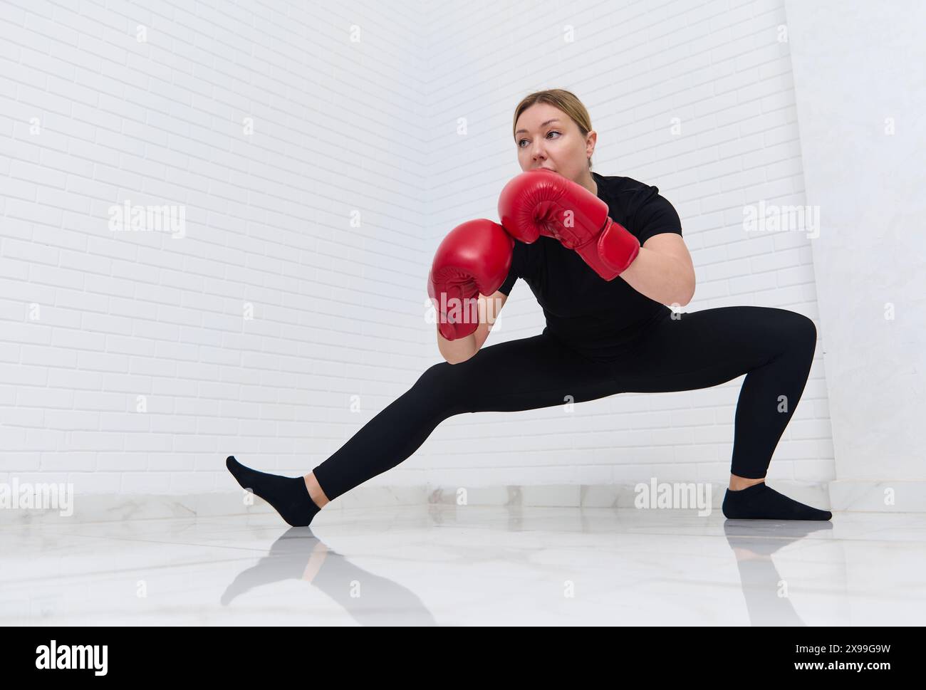 European woman fighter boxer in red boxing gloves, doing stretching ...