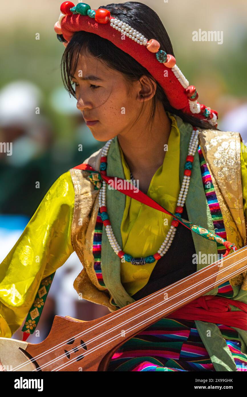 Portrait of a young Ladakhi girl in traditional attire playing a ...