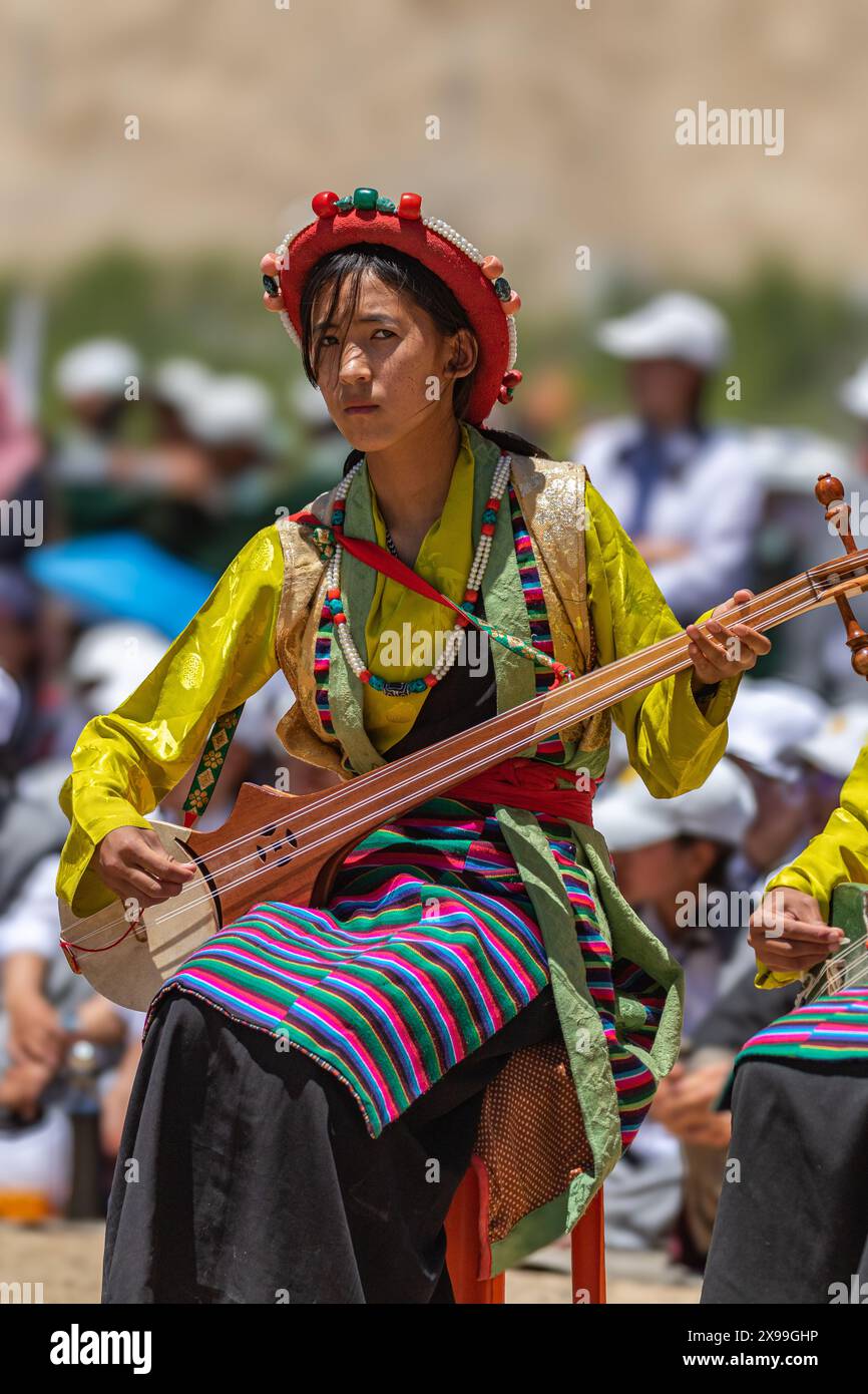 Portrait of a young Ladakhi girl in traditional attire playing a ...