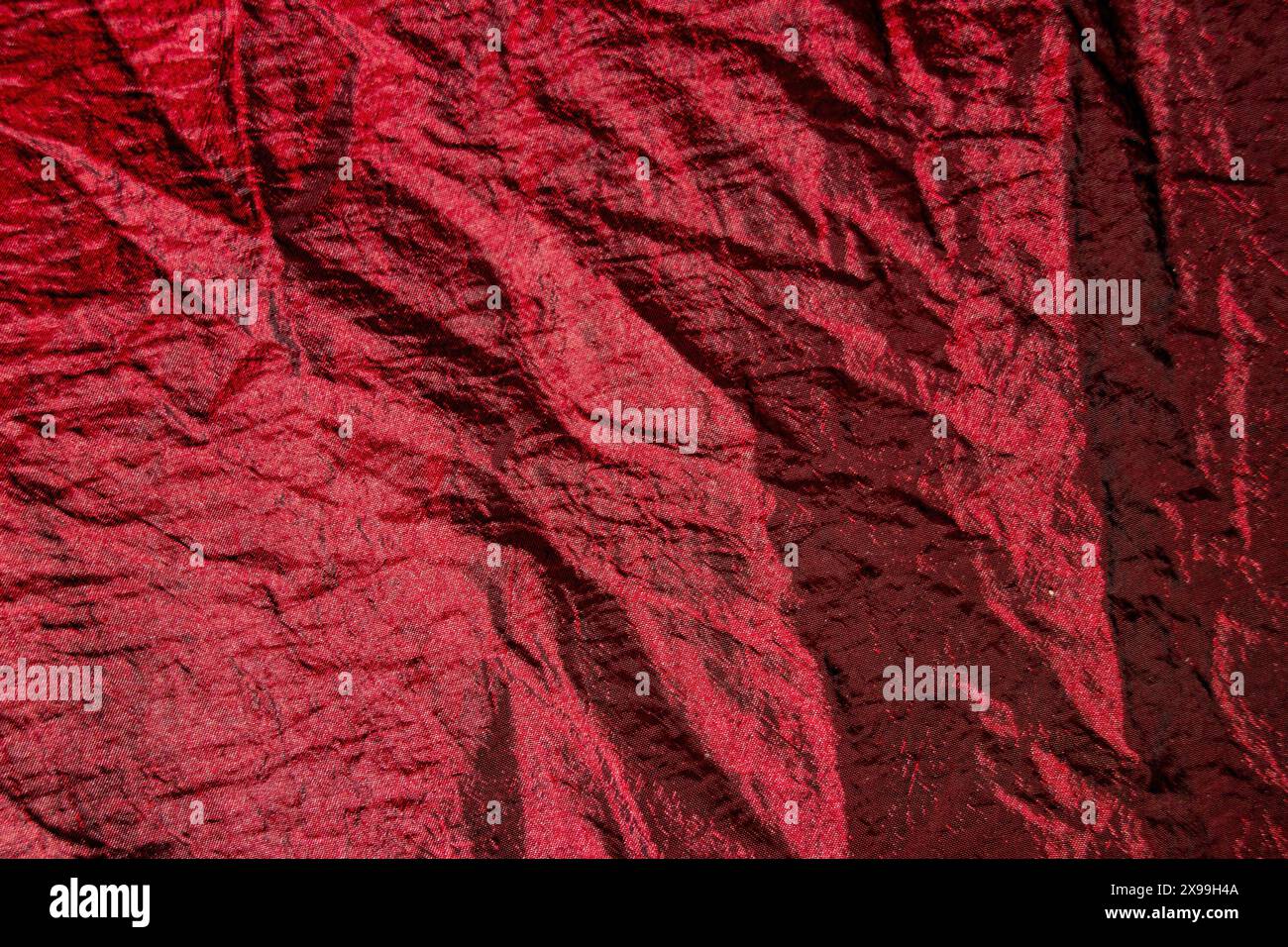 Wine red crumpled fabric on a bed with strong shadows Stock Photo - Alamy