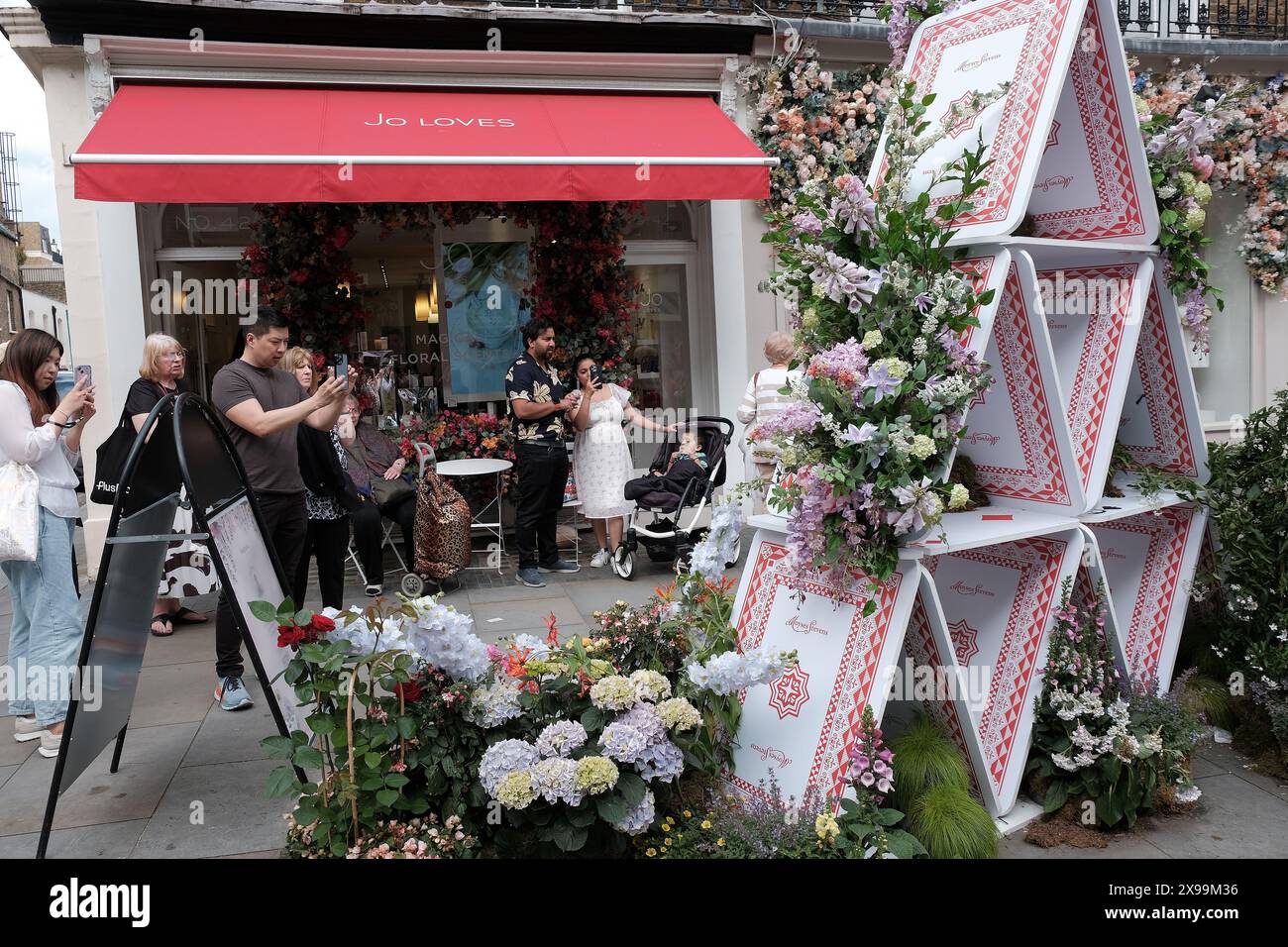 Tourists photograph floral displays outside shops in and around Chelsea ...