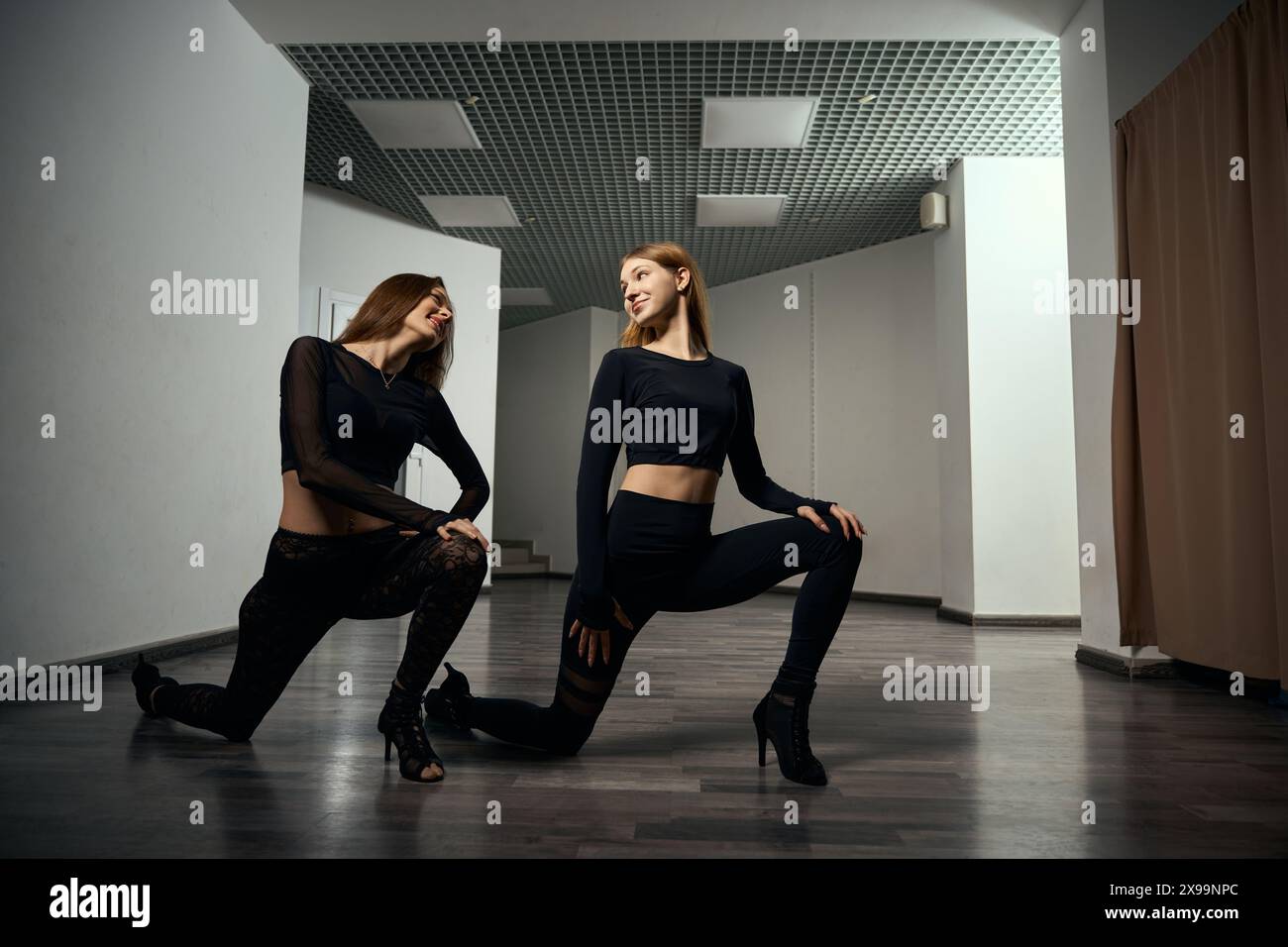 Stiletto dancers doing leg stretching exercise before dance session ...