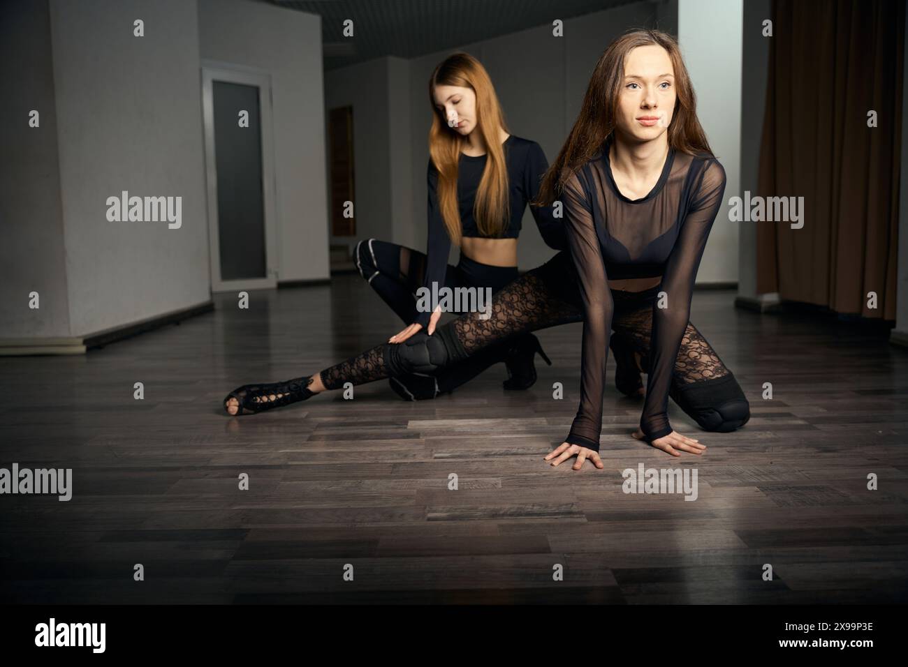 Female dancer doing leg stretch before stiletto dance assisted by ...