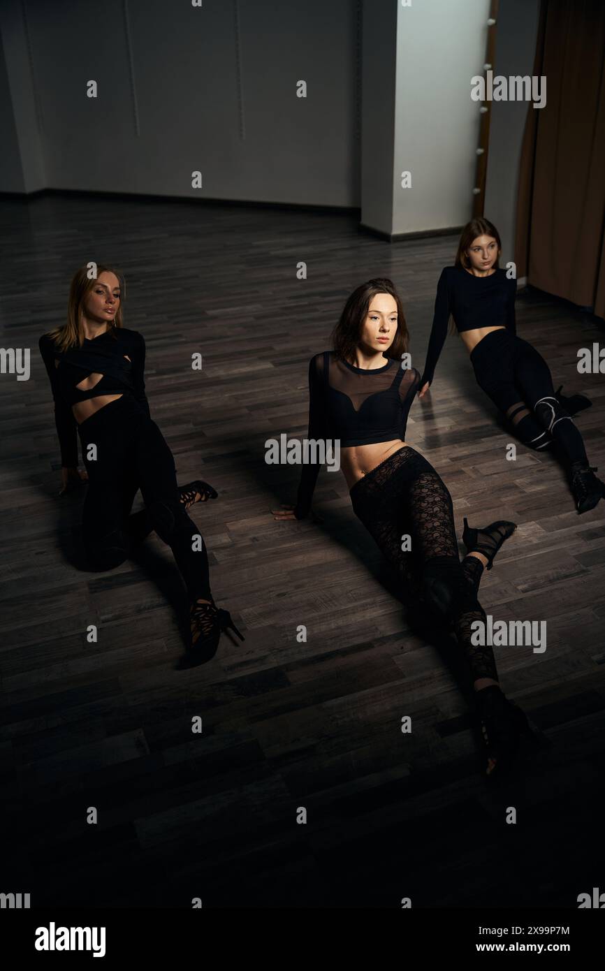 Three women in stilettos performing floorwork dance in studio Stock ...