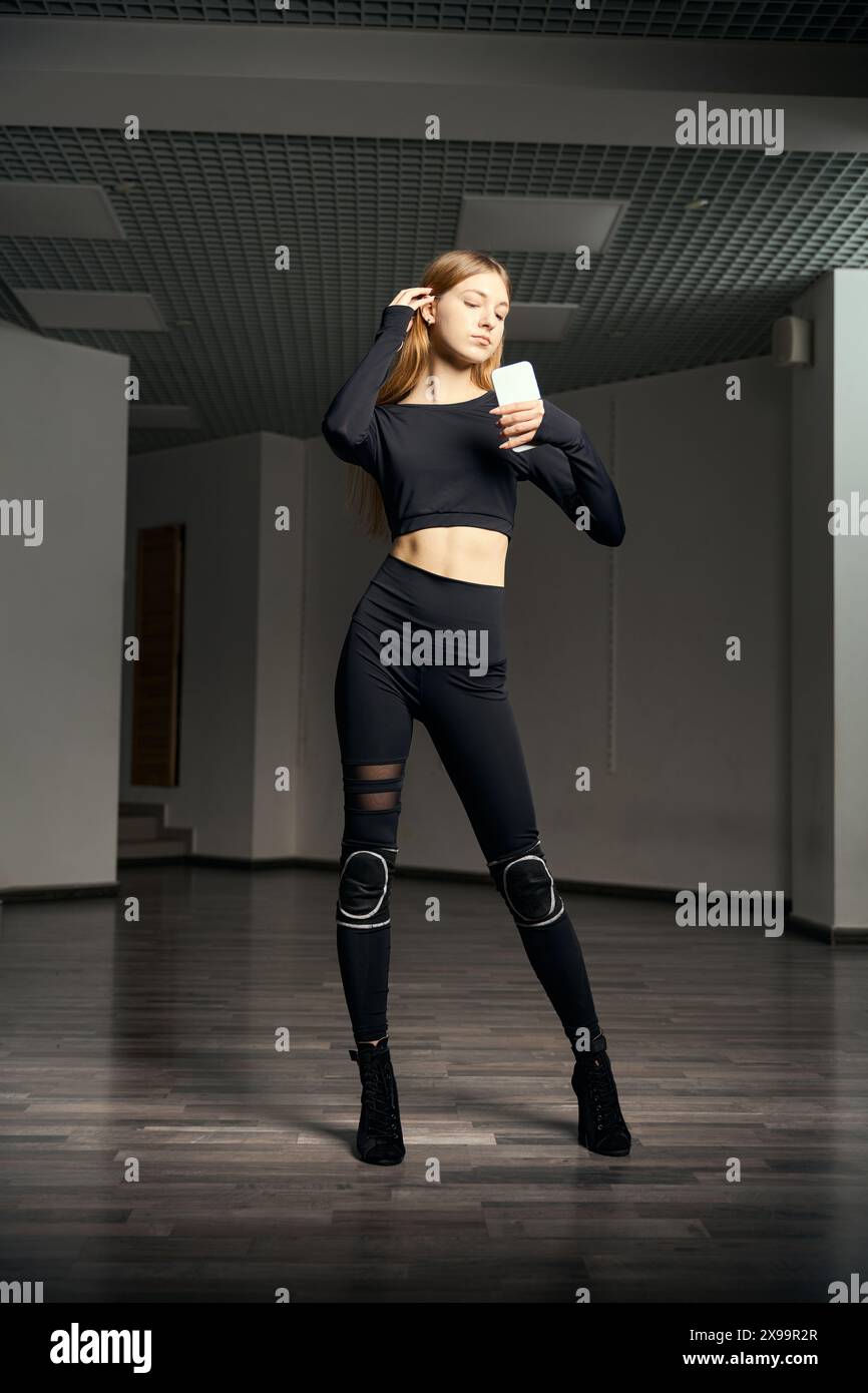 Female with smartphone in hand striking pose for stiletto dance Stock ...
