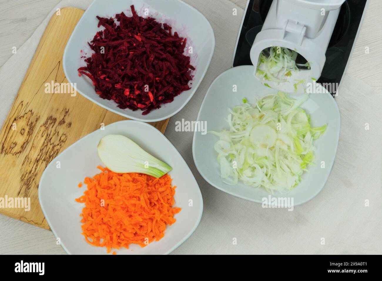 Onion, carrot and beet in a vegetable cutter on kitchen. Chopped onion ...