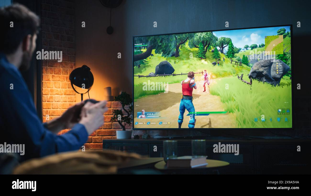 Young Man Spending Time at Home, Sitting on a Couch in Stylish Loft Apartment and Playing Arcade ...