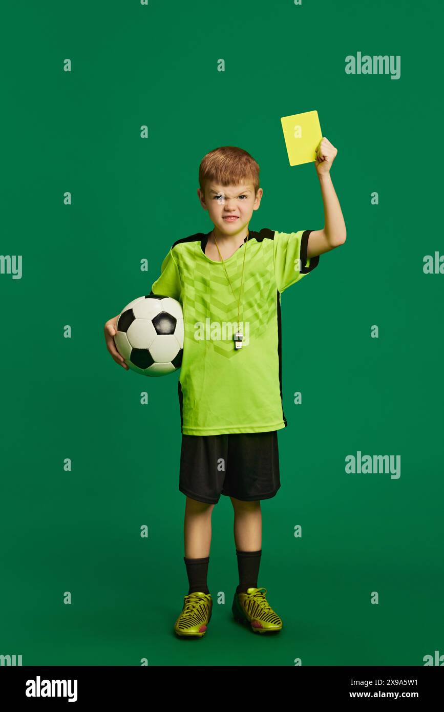 Boy dressed as soccer referee holding ball and yellow card with angry ...