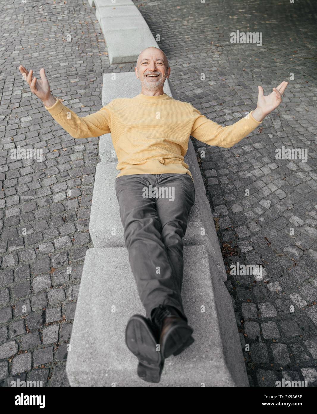 Senior Man in Yellow Sweater Reclining on an Urban Bench With Arms Open ...