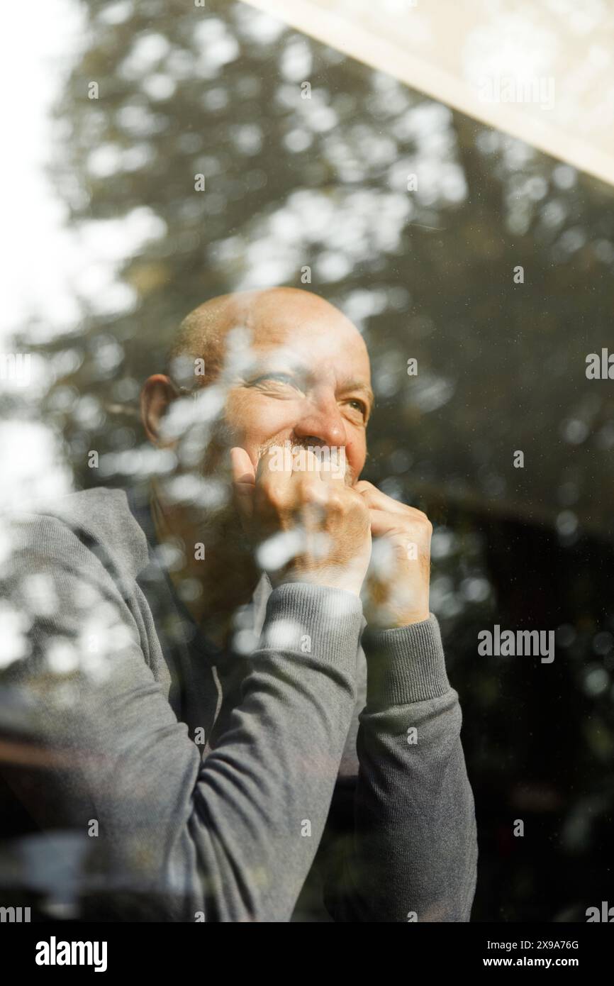 Happy senior man with a beard smiling with his hands on his chin behind ...