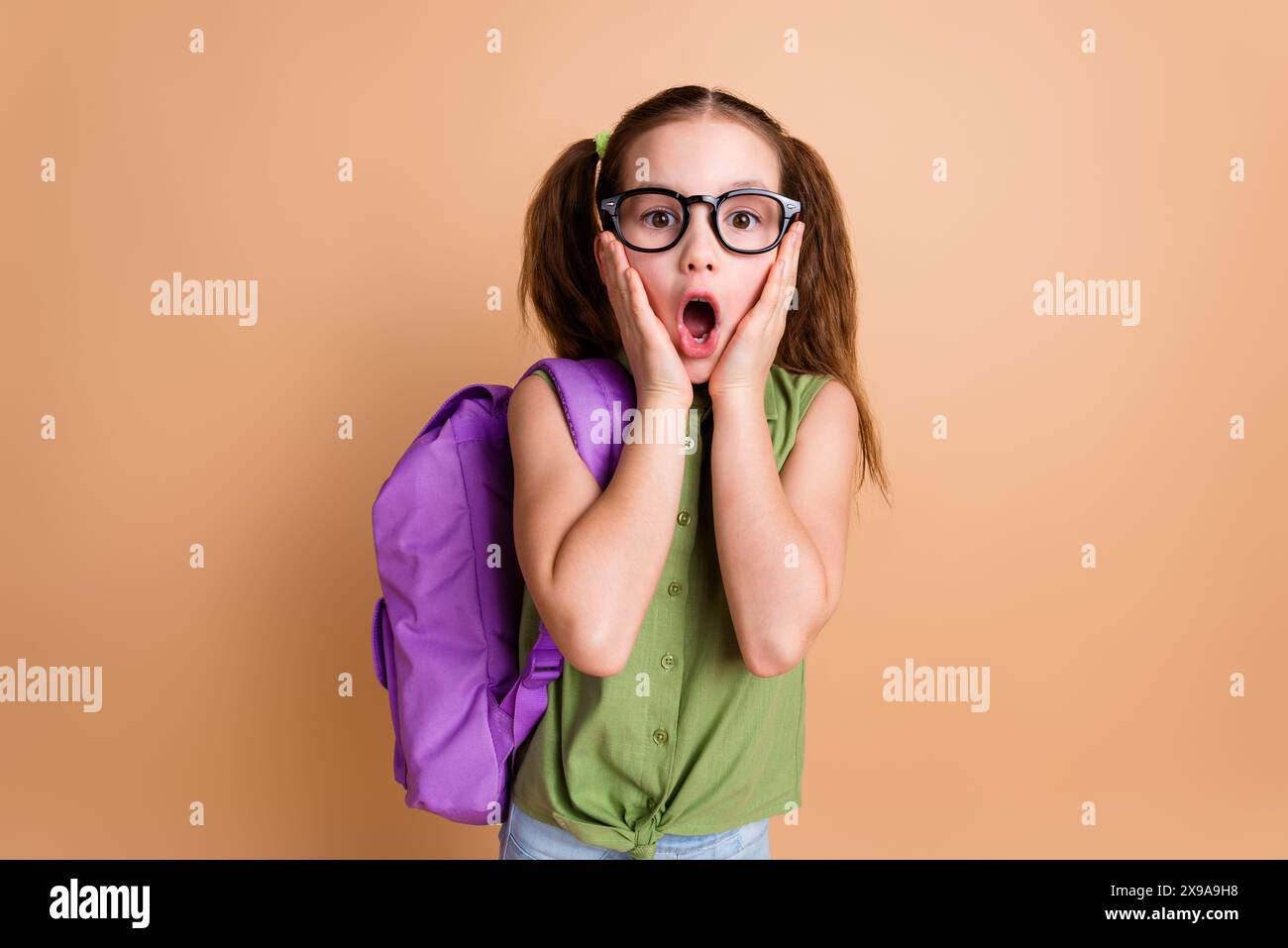 Photo of shocked kid girl pupil open mouth touch face hold rucksack ...