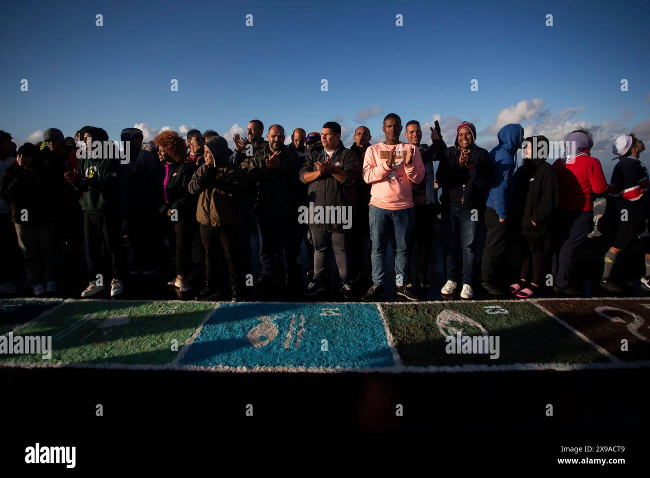 People stand behind rugs made of colored salt and sustainable materials ...