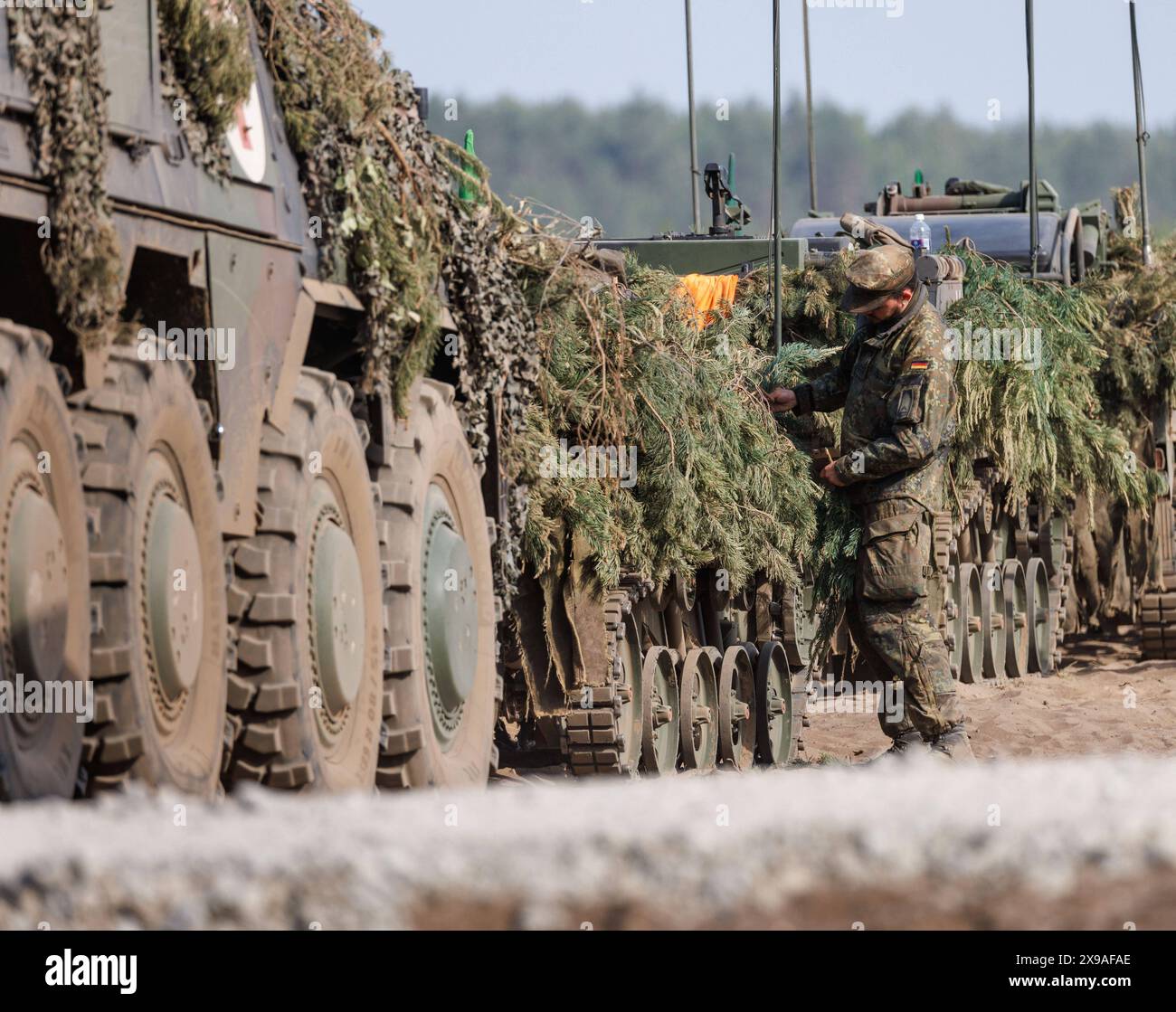 Ein Bundeswehr-Soldat arbeitet an der Tarnung eines Schuetzenpanzer ...