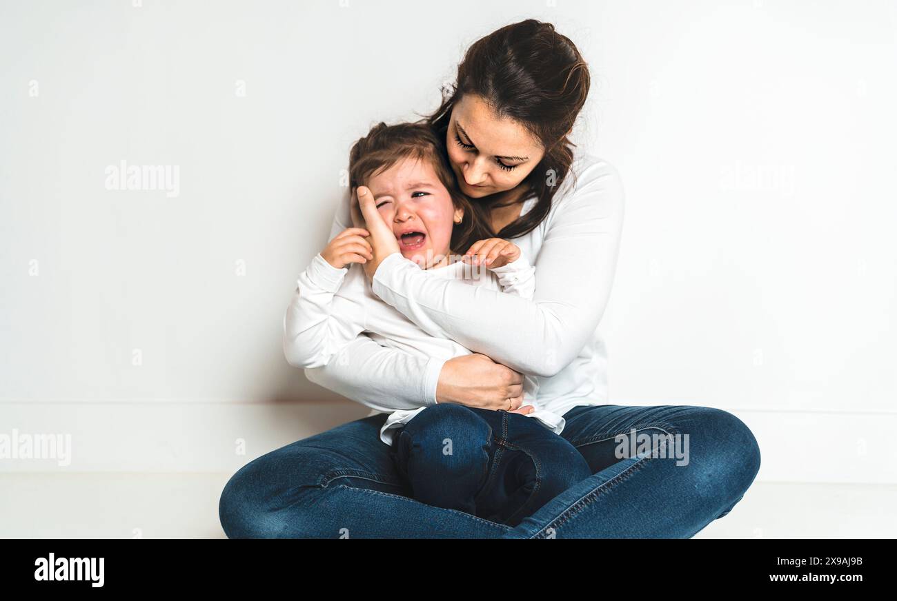 Mother comforting her crying little girl on white Stock Photo - Alamy