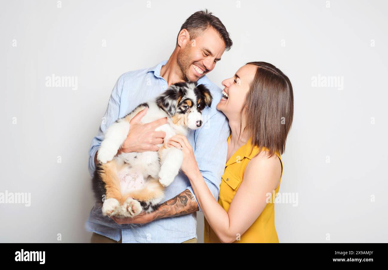 Handsome couple with her Australian Berger puppy on studio Stock Photo ...