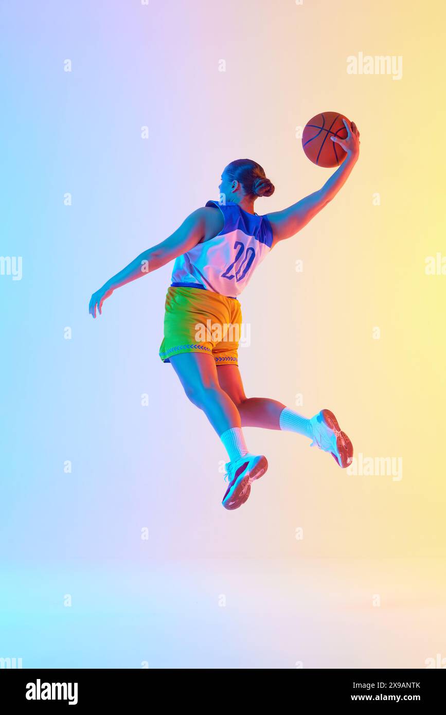Young athletic woman wearing sports uniform doing perfect slam dunk in ...