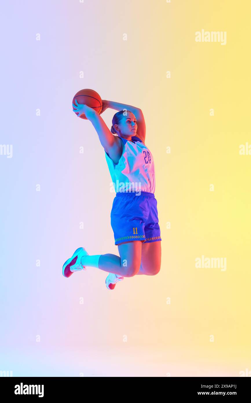 Powerful dunk. Young woman basketball player jumping in mid-air to make ...