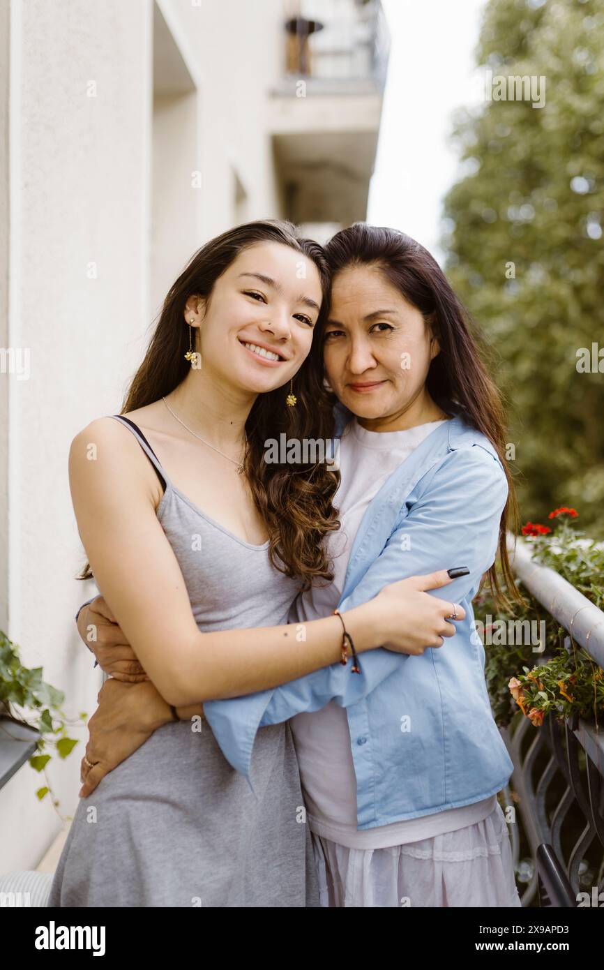 Portrait of mother and daughter standing with arms around while ...