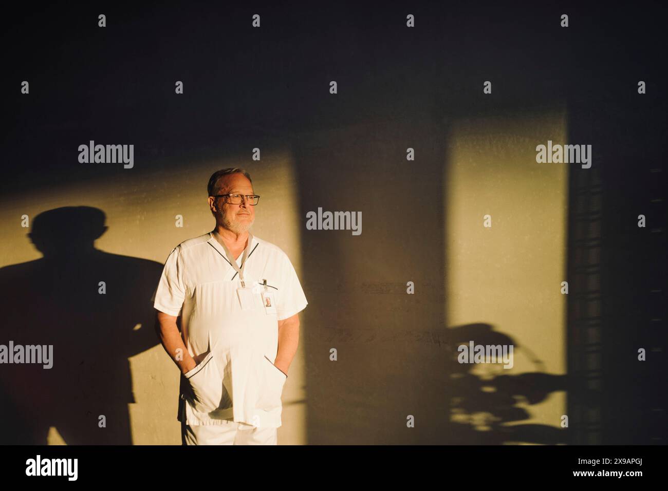 Thoughtful senior doctor standing in front of wall at hospital Stock ...