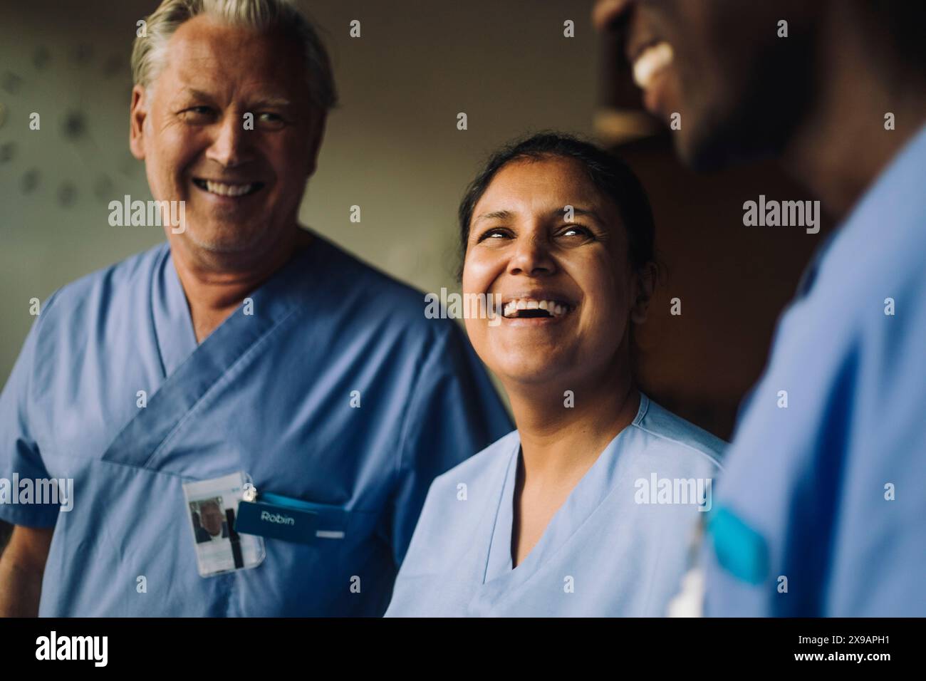 Cheerful multiracial male and female doctors in blue scrubs at hospital ...