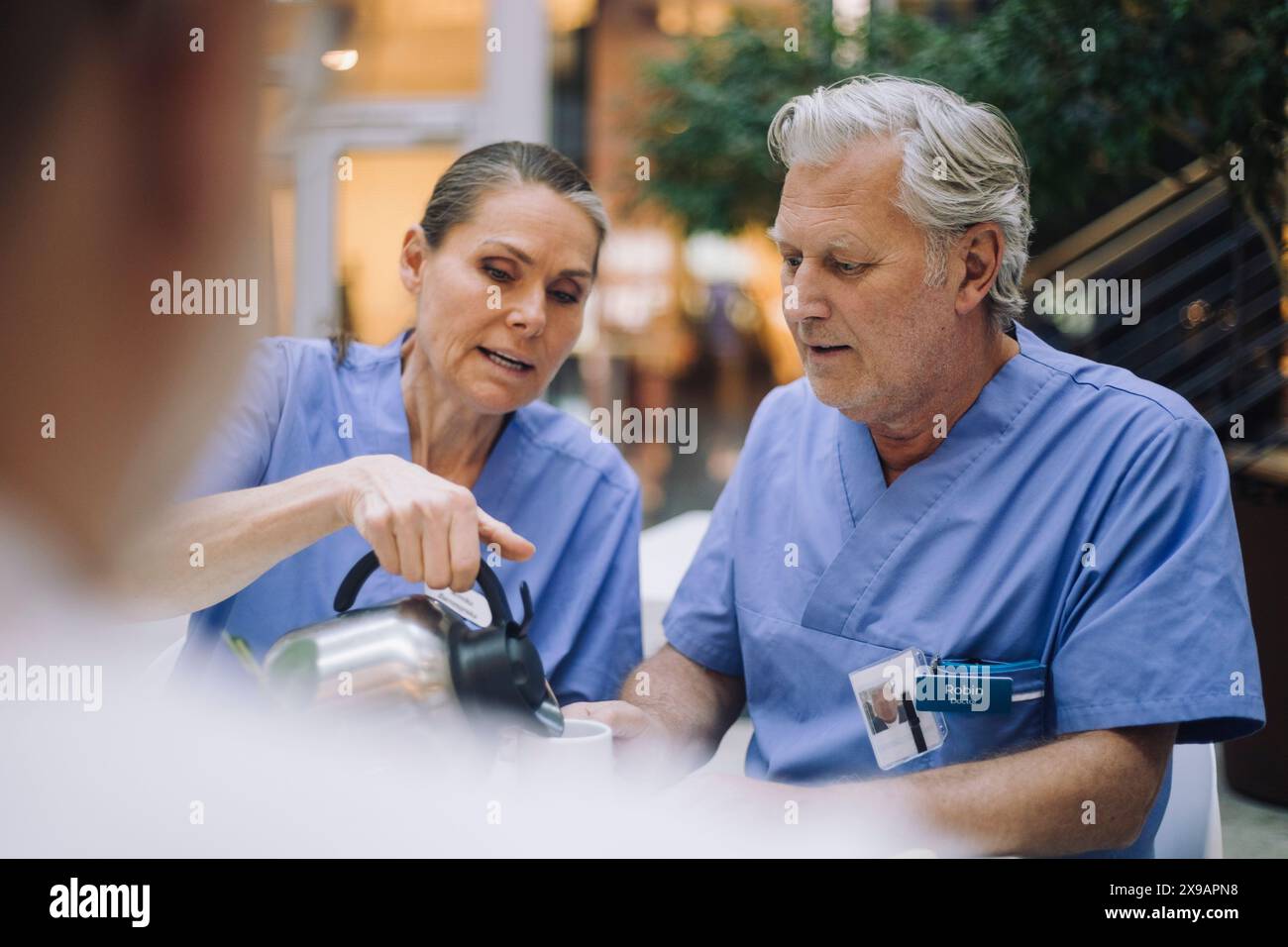 Female doctor pouring coffee for colleague in cafeteria at hospital ...