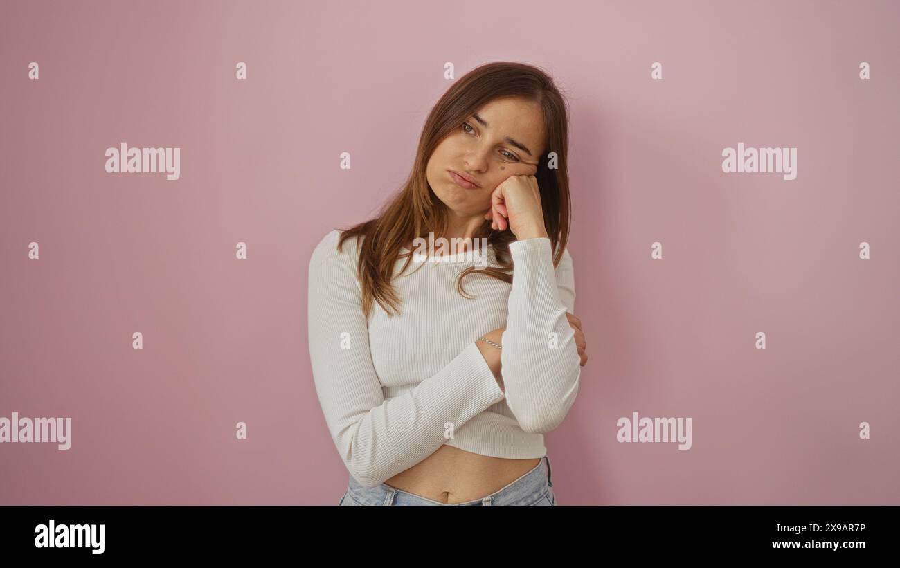 A young caucasian woman looks bored against a pink background ...
