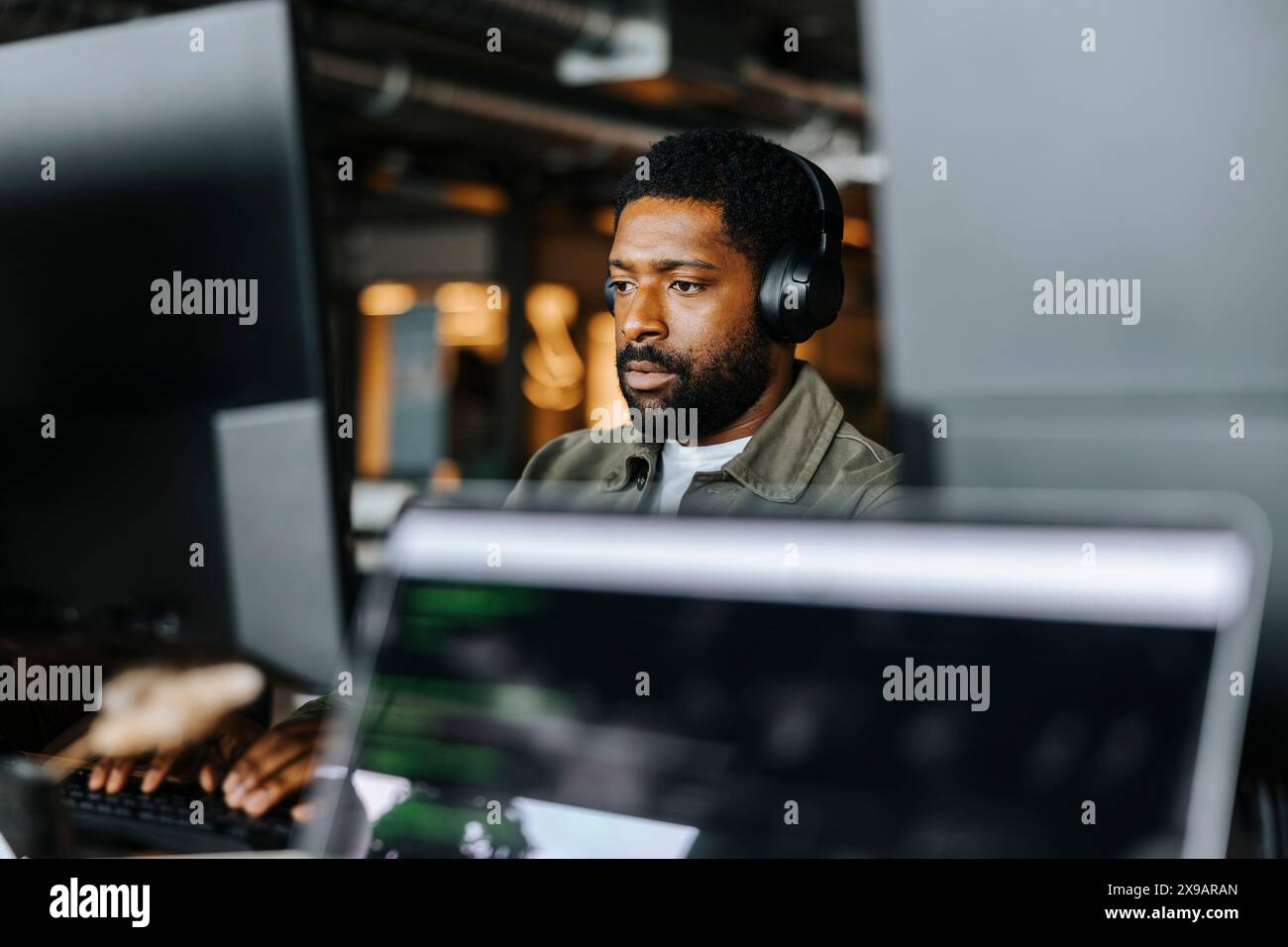 Focused male programmer working with wireless headphones at office ...