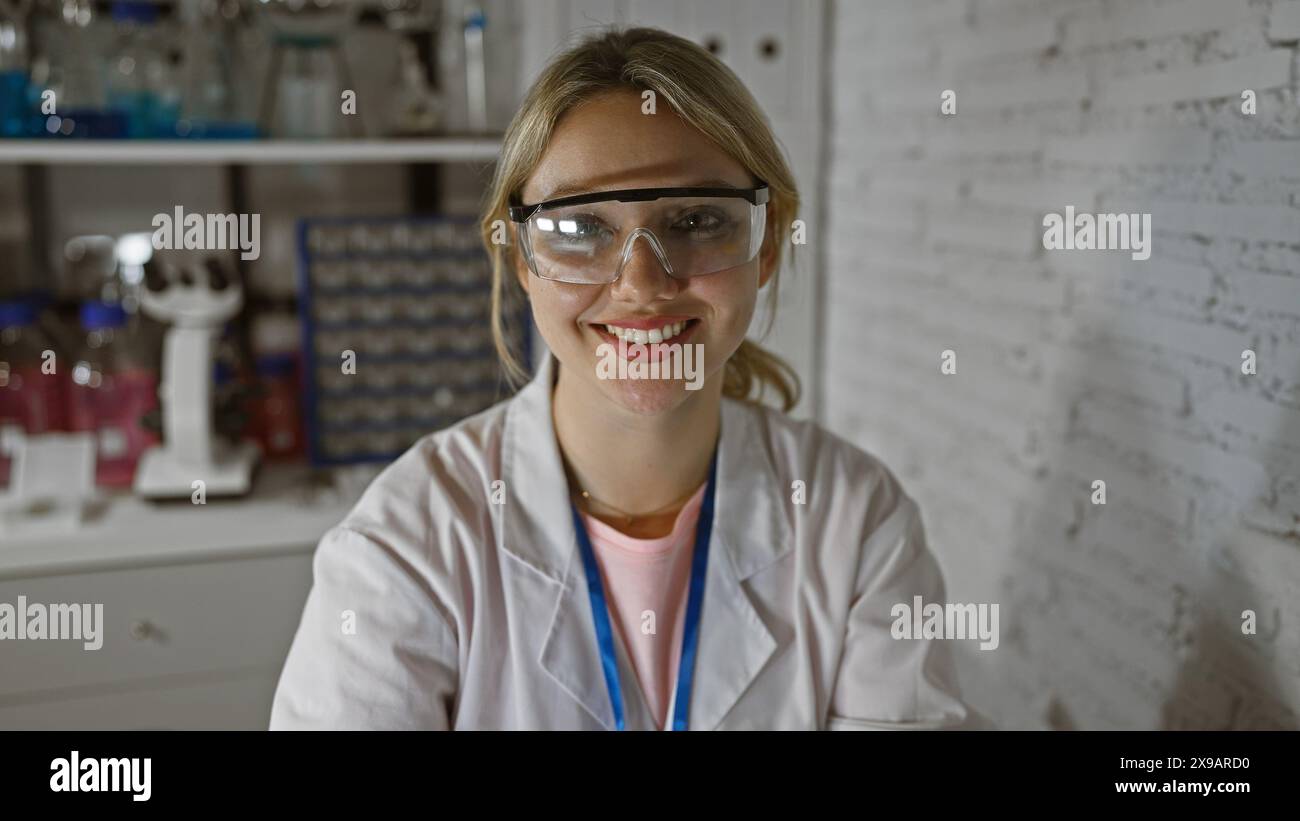 Smiling young woman scientist wearing safety glasses in a laboratory ...