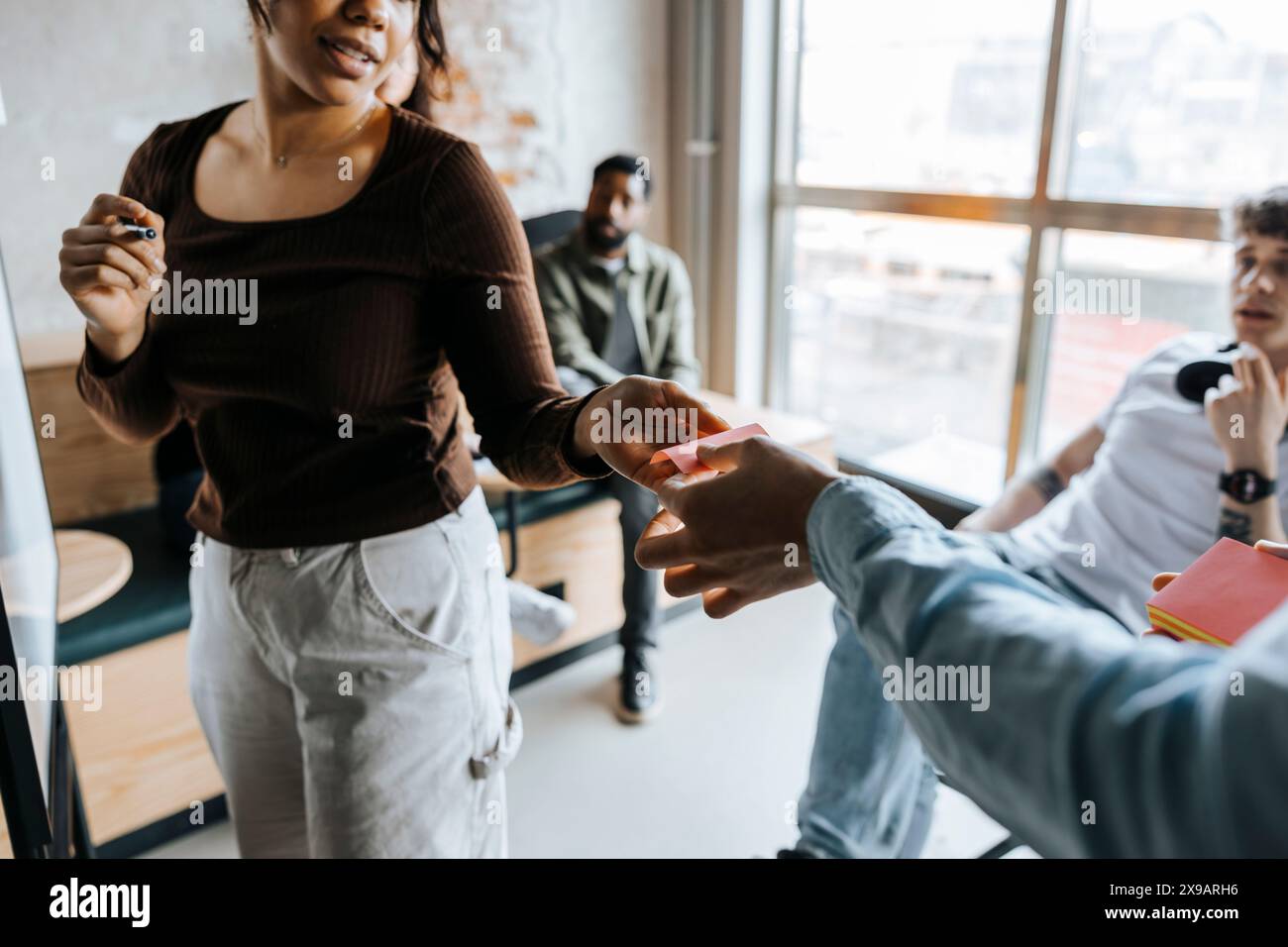 Female entrepreneur passing adhesive note of colleague in meeting at ...