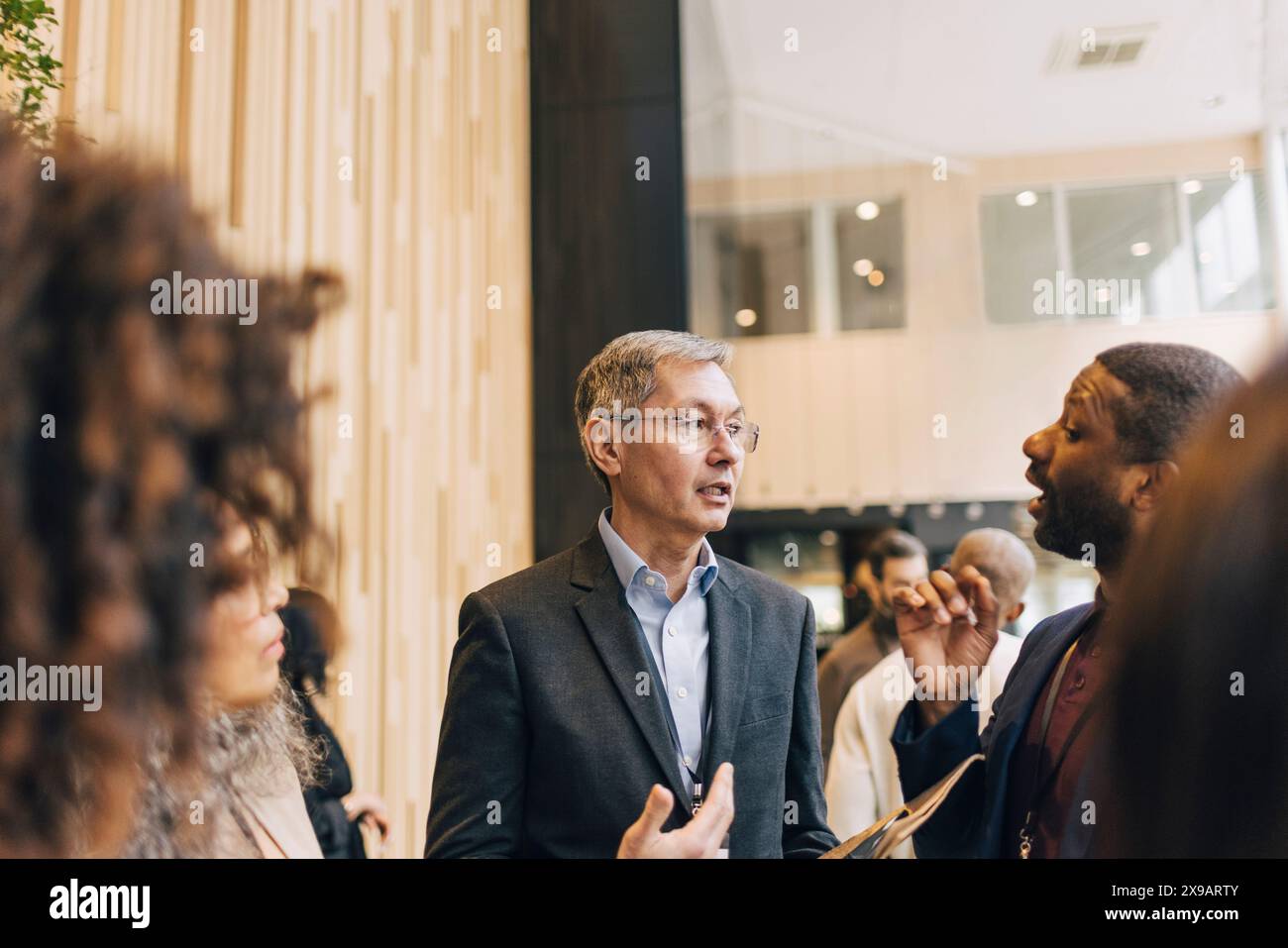 Senior businessman discussing with male delegate during networking ...