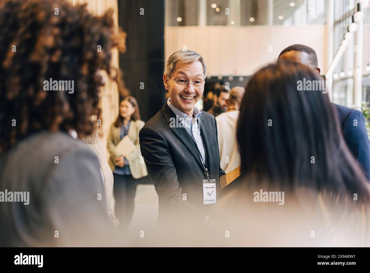 Happy senior male entrepreneur talking with delegates during networking ...