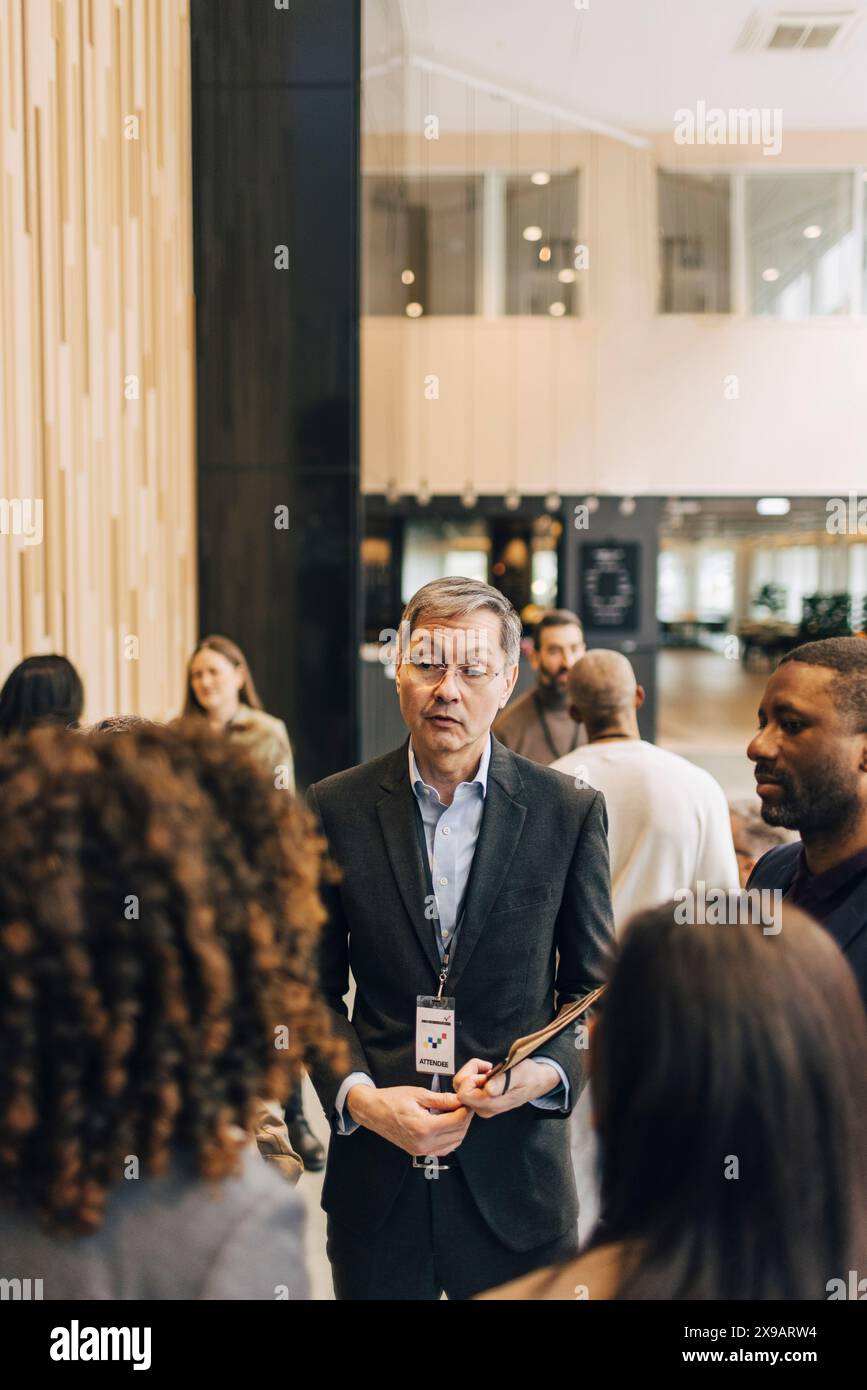 Senior male entrepreneur discussing with delegates during networking ...