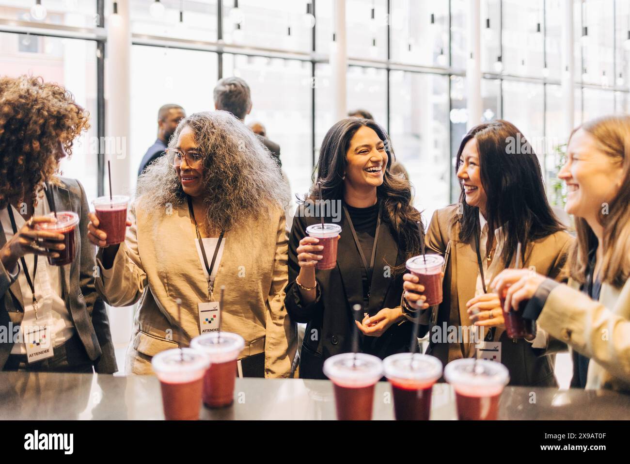 Happy female delegates having smoothies during break time at convention ...