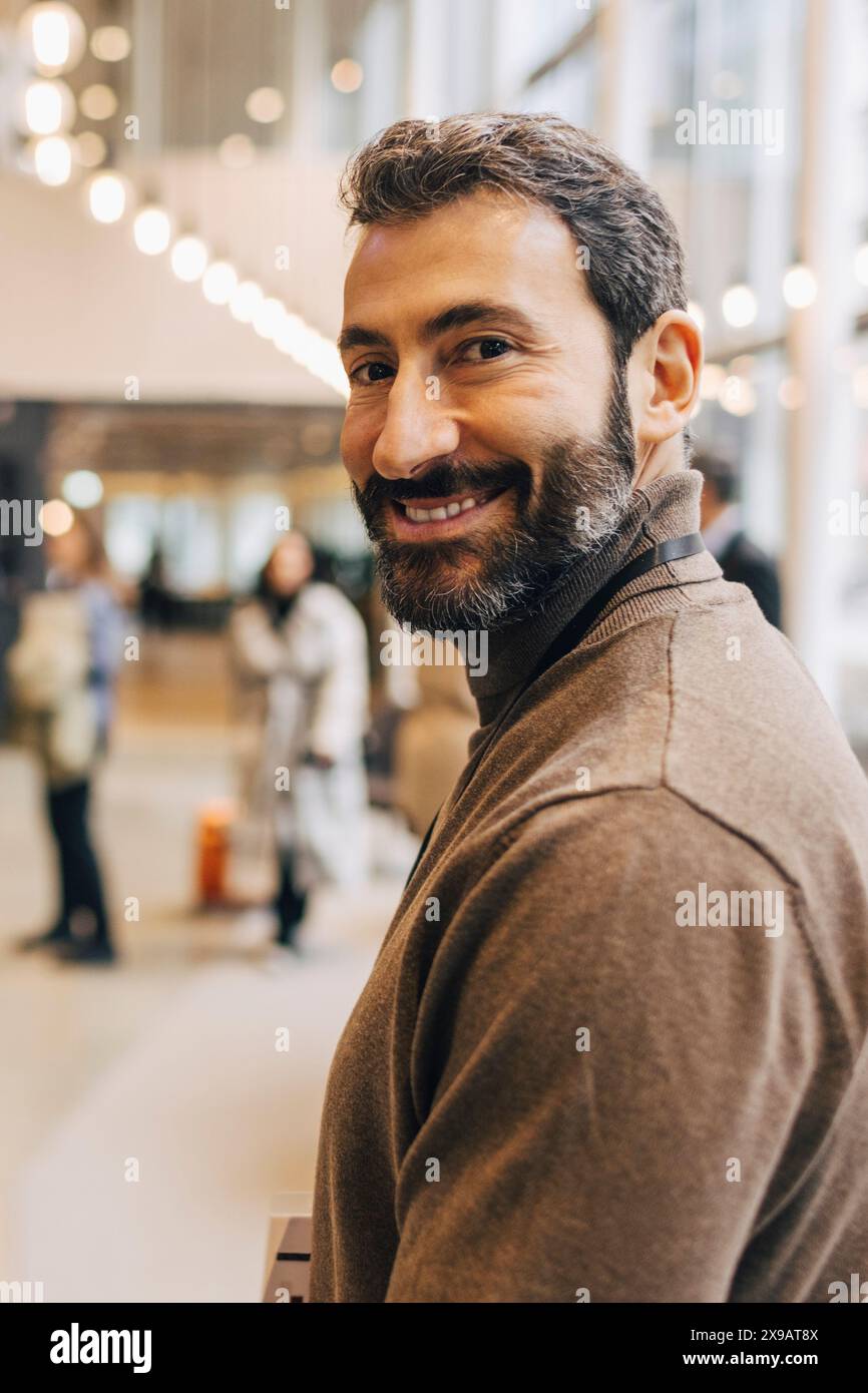 Side view portrait of smiling male entrepreneur at convention center ...