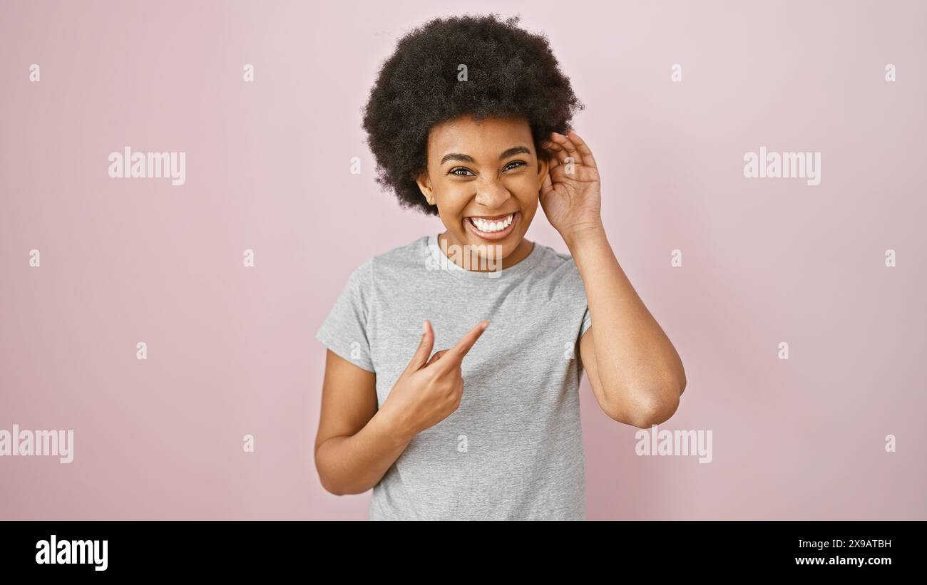 Smiling african american woman with curly hair gestures shush sign ...